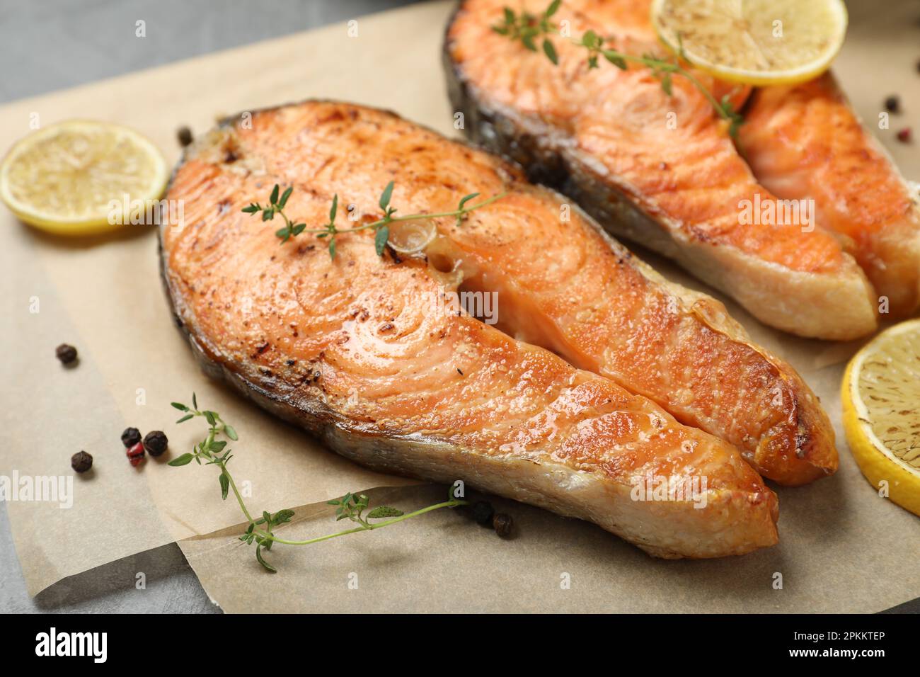 Delicious roasted fish with thyme and lemon on parchment paper, closeup ...