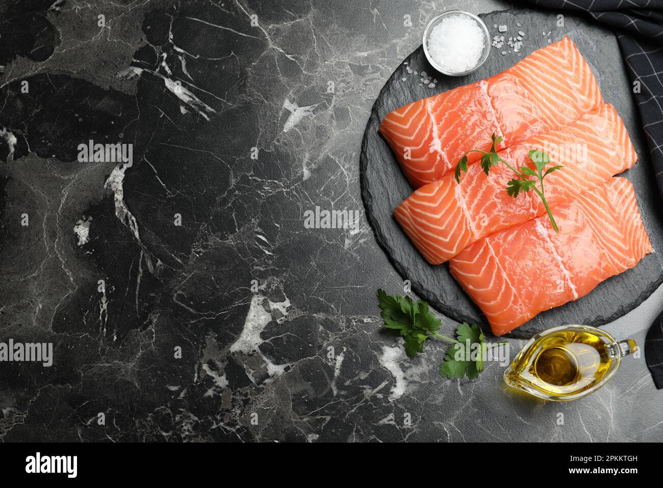 Flat lay composition with fresh raw salmon on black marble table, space ...