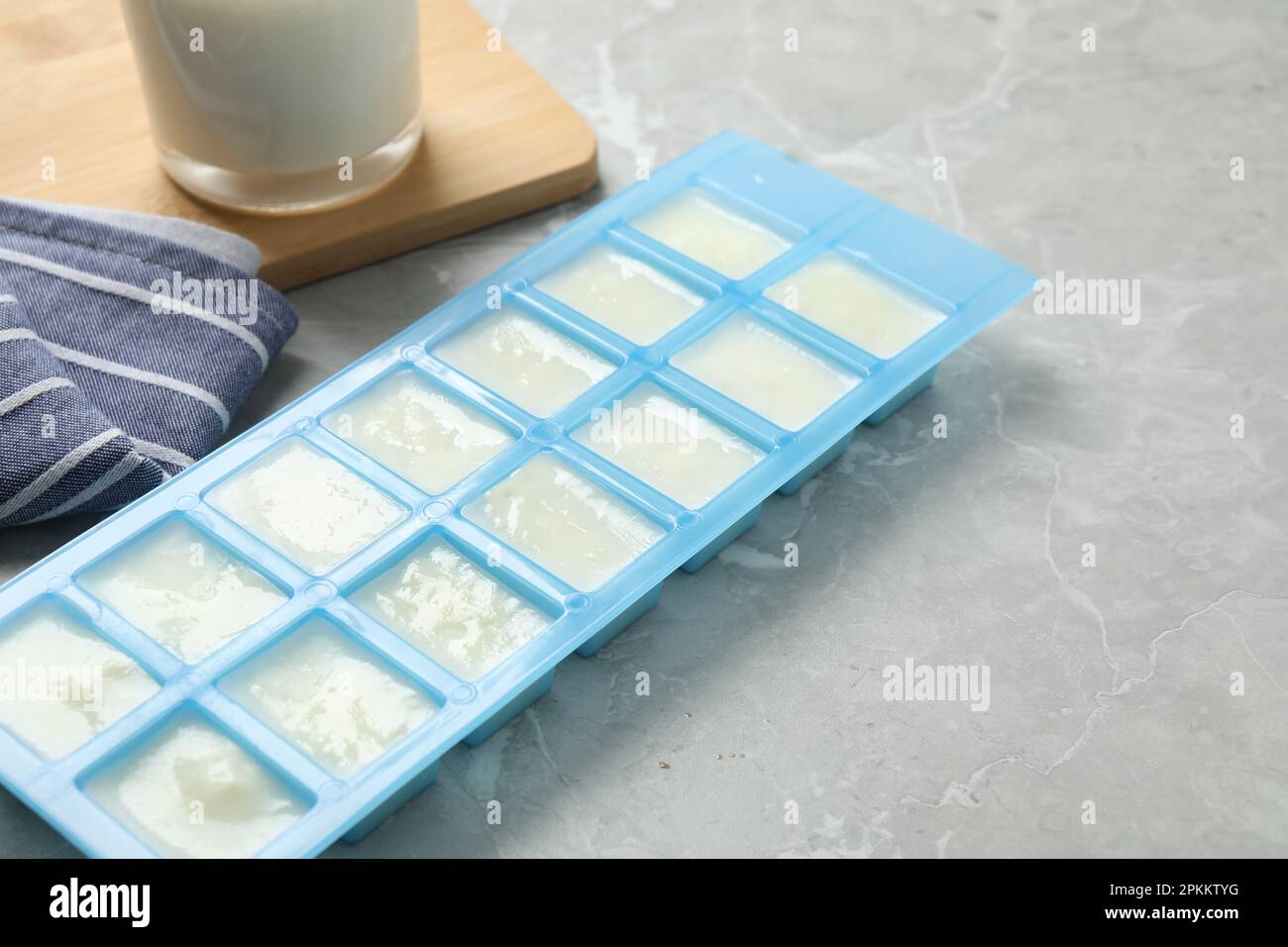 Ice cube tray with frozen milk on grey table Stock Photo - Alamy