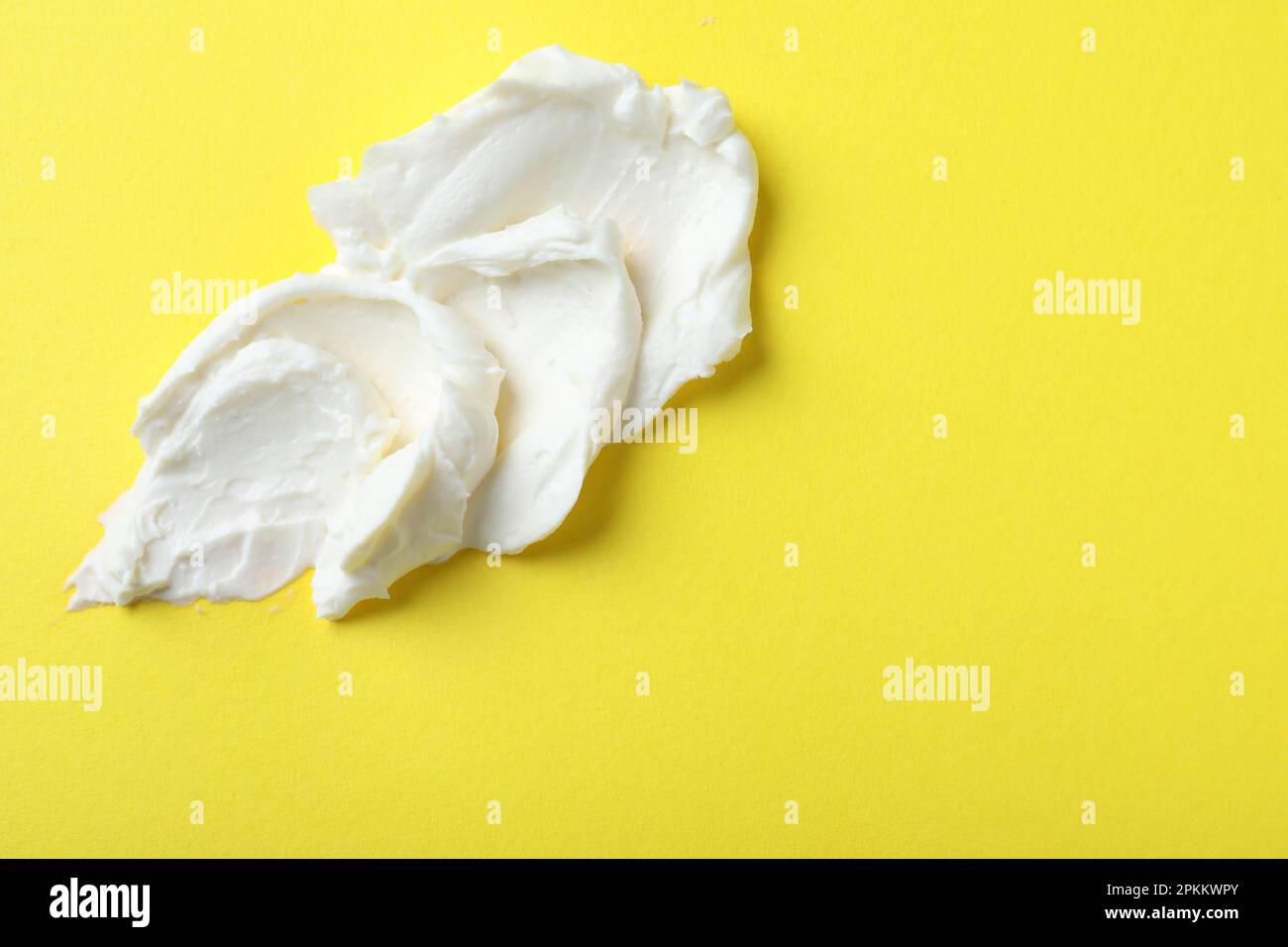 Smear of delicious cream cheese on yellow background, top view. Space ...