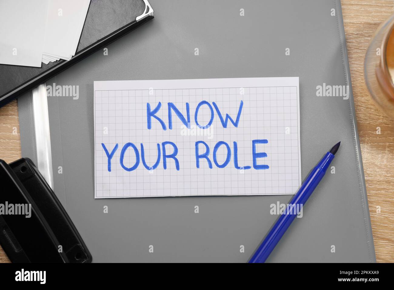 Note with phrase Know Your Role and stationery on wooden table, flat ...