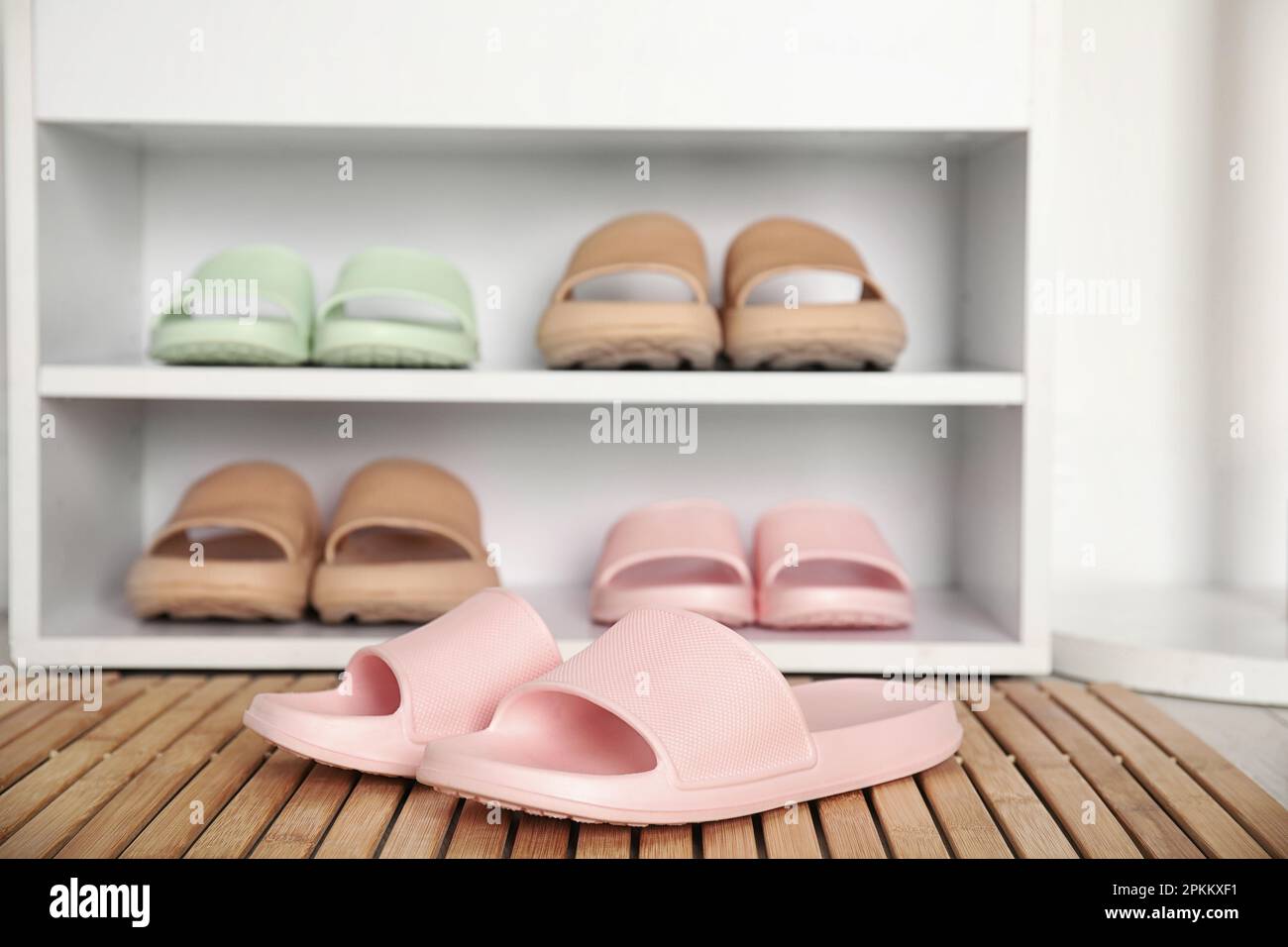 Stylish rubber slippers and storage cabinet with shoes indoors Stock ...