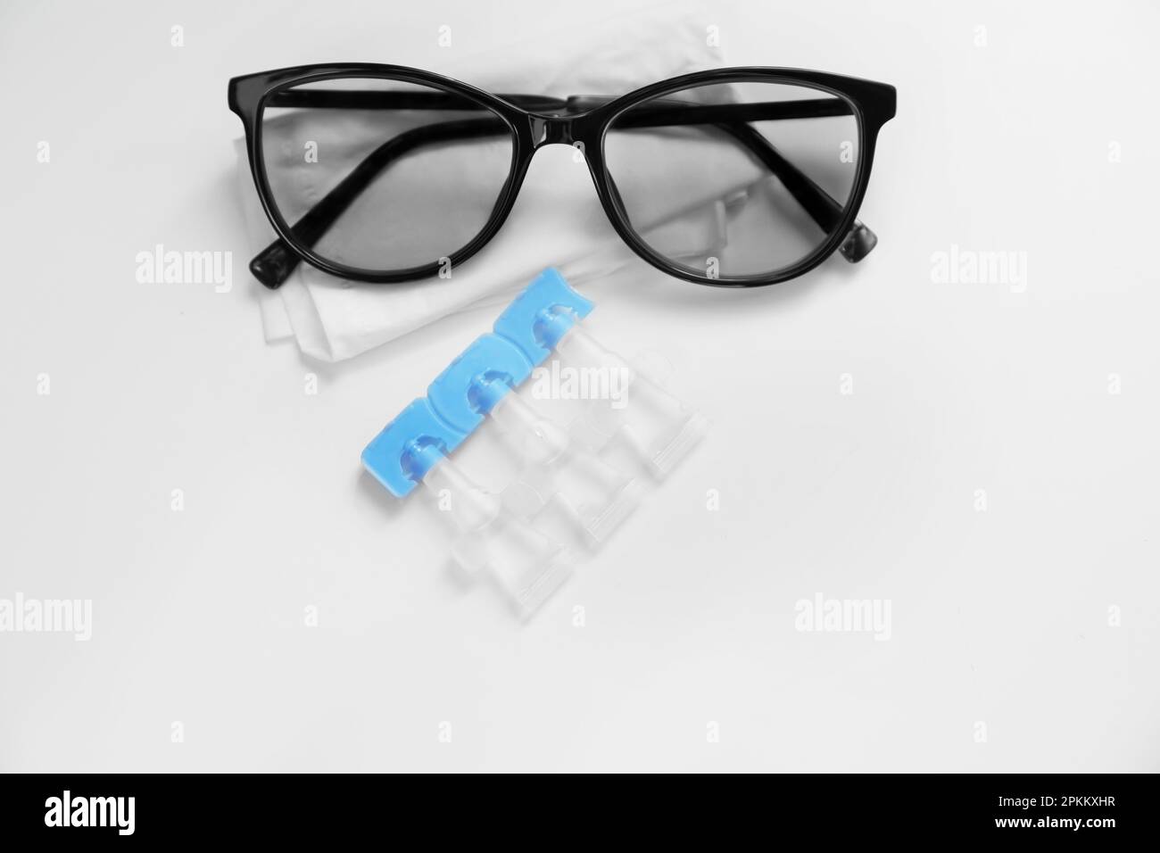 Single dose eye drops, glasses and fabric on white table, above view ...