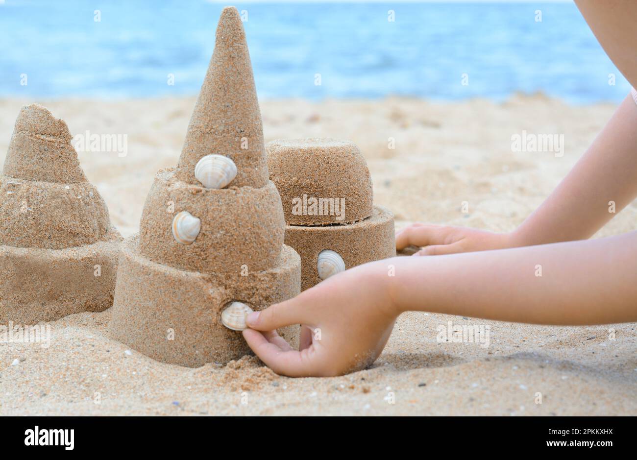 Child decorating sand castle with shell on beach, closeup Stock Photo ...