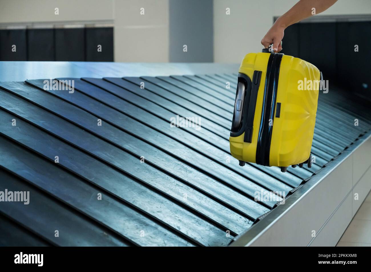 A woman takes a suitcase from the baggage carousel Stock Photo - Alamy