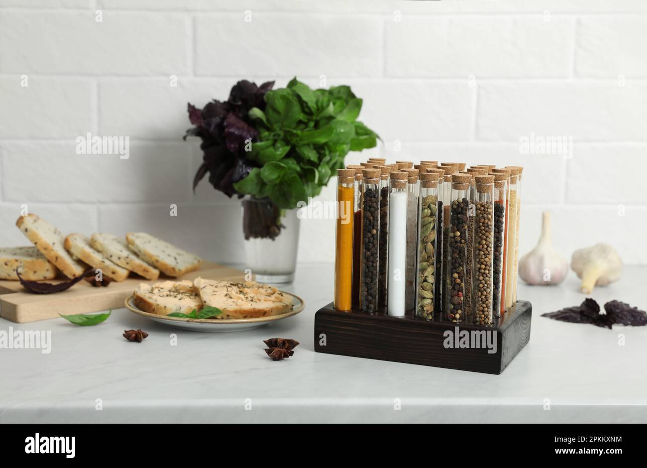 Glass tubes with different spices and plate of sandwiches on kitchen ...