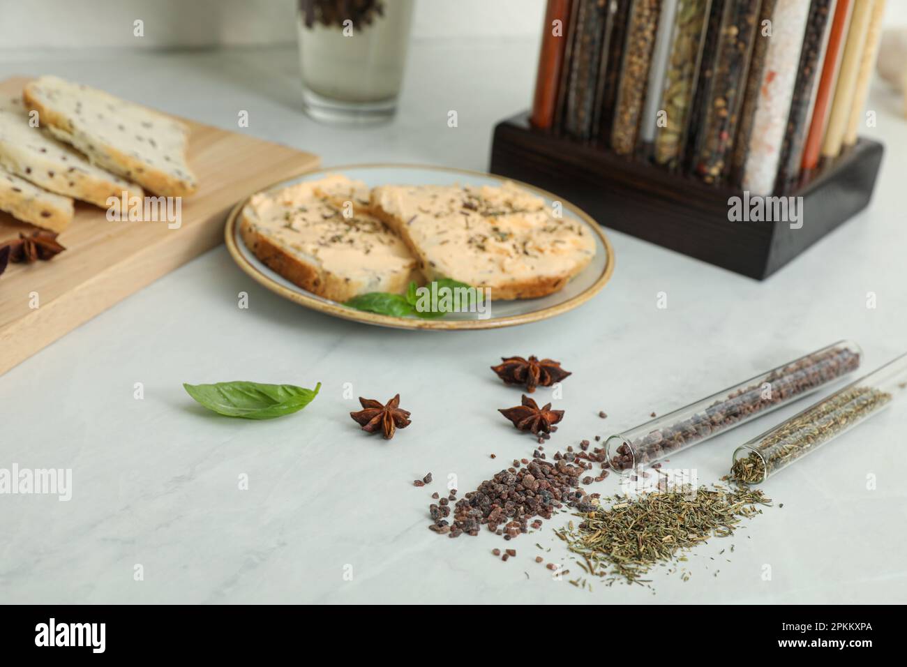 Glass tubes with black salt and Italian herb mix near plate of ...