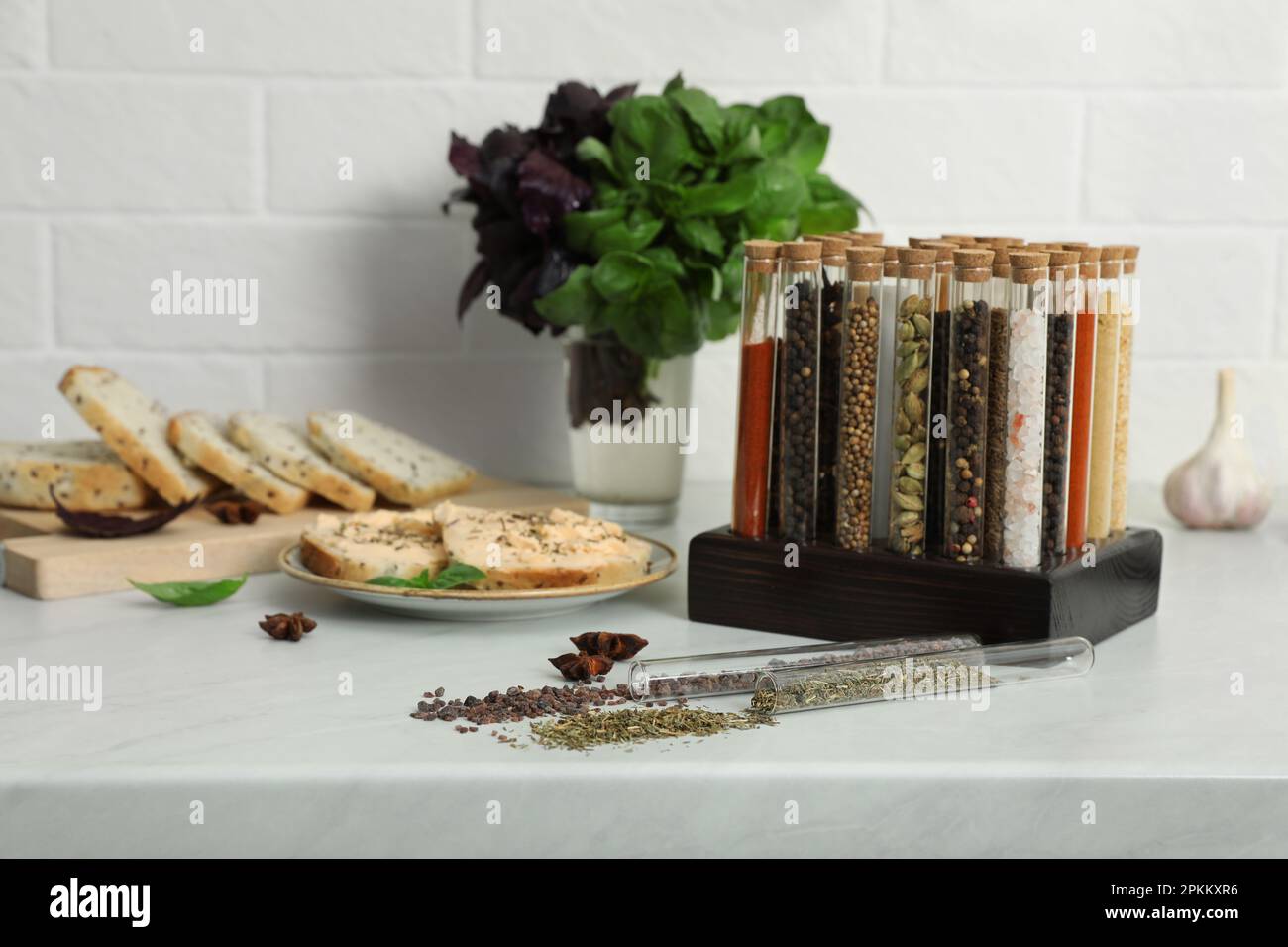 Glass tubes with different spices and plate of sandwiches on kitchen ...