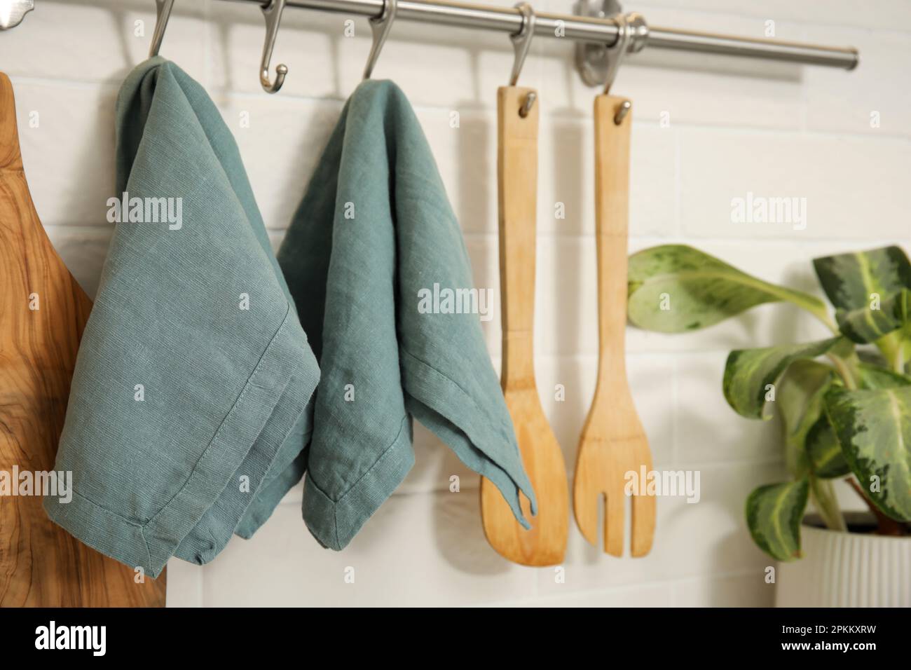 Clean towels and utensils hanging on rack in kitchen Stock Photo - Alamy