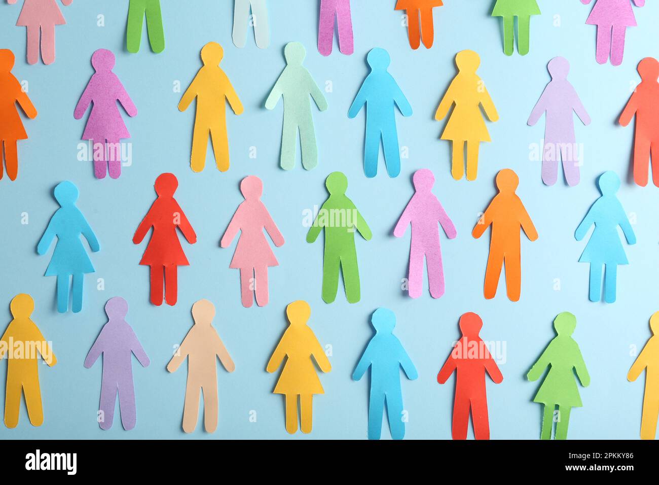 Many different paper human figures on light blue background, flat lay ...