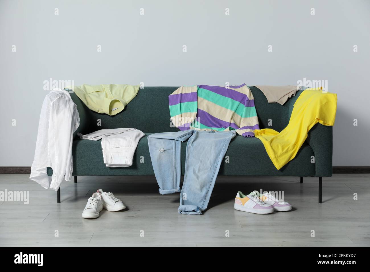 Messy pile of clothes on sofa and shoes in living room Stock Photo - Alamy