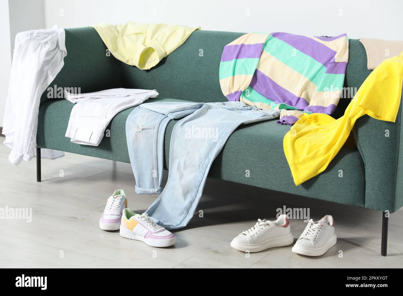 Messy pile of clothes on sofa and shoes in living room Stock Photo - Alamy