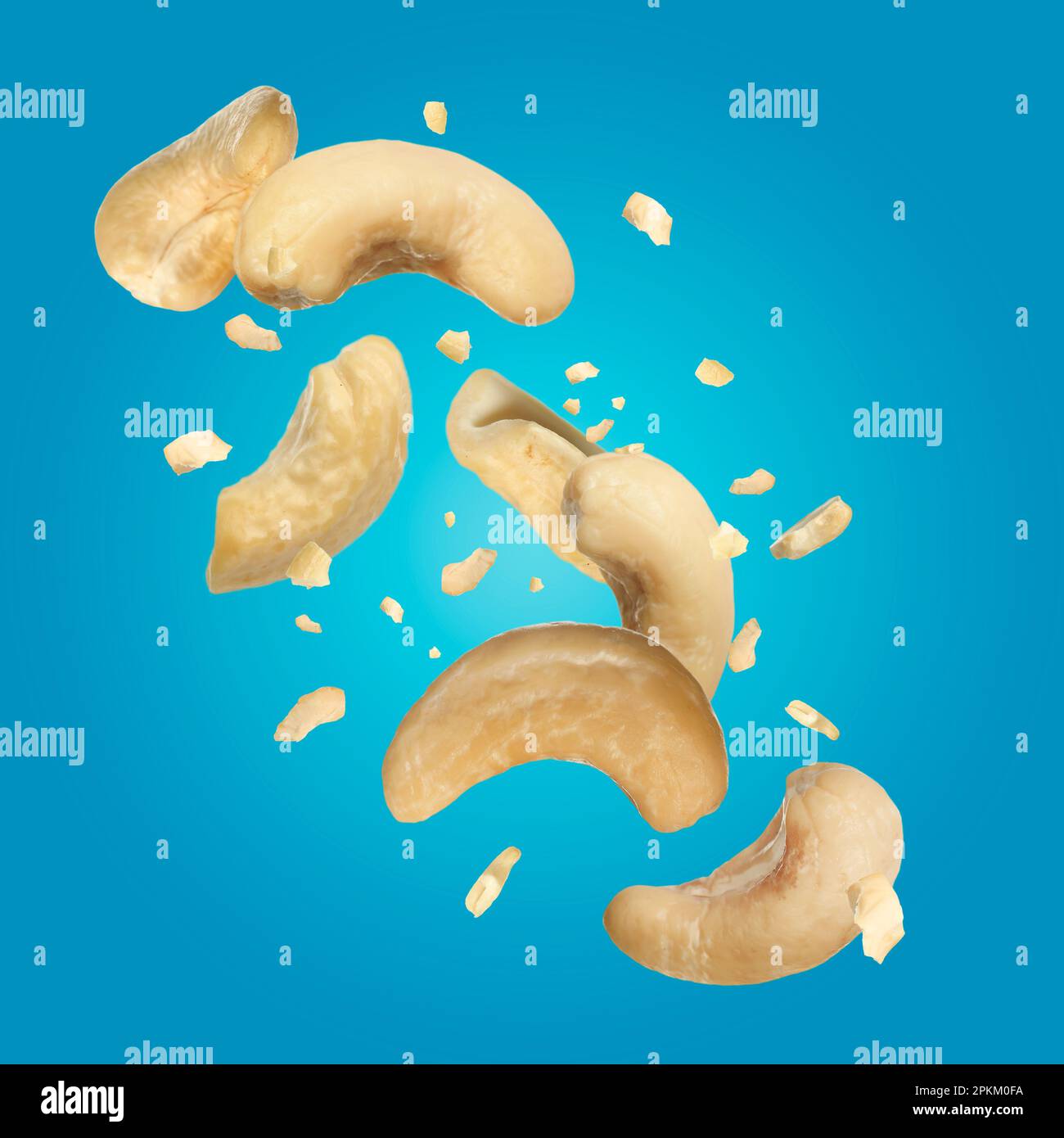 Tasty cashew nuts flying on turquoise background Stock Photo - Alamy
