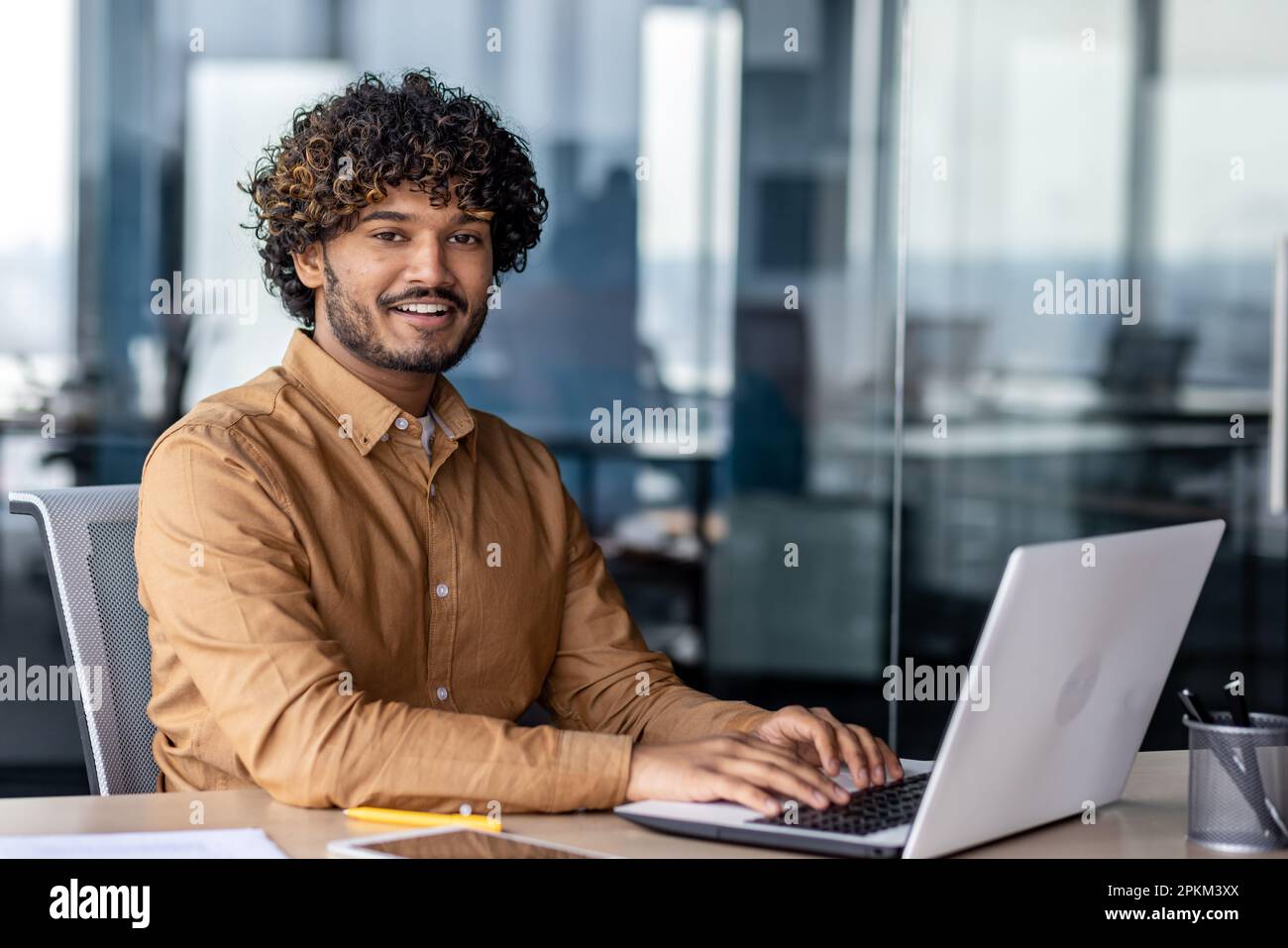 Portrait of young successful Indian man at workplace inside office ...