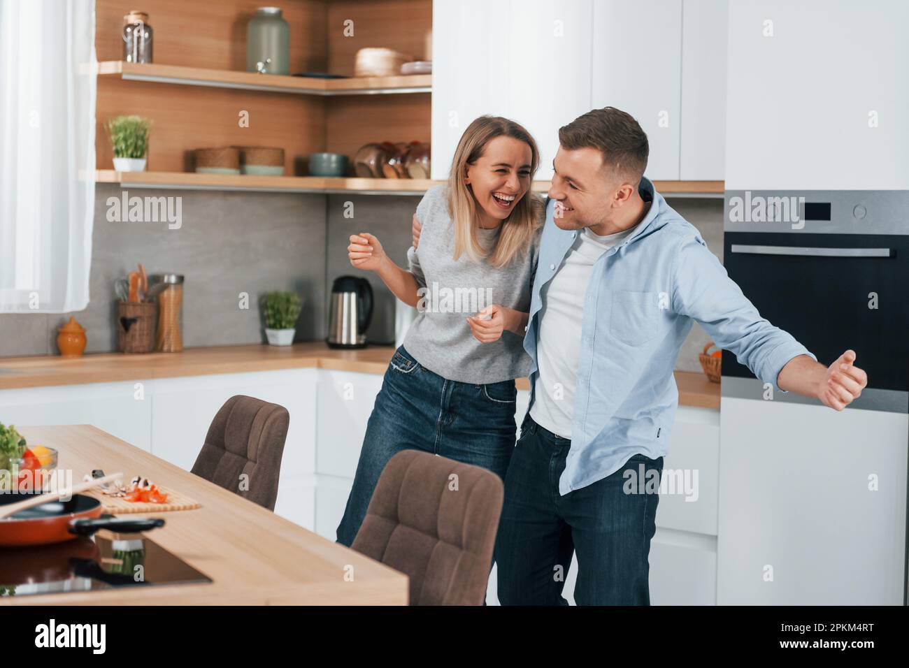 Positive emotions. Couple preparing food at home on the modern kitchen ...