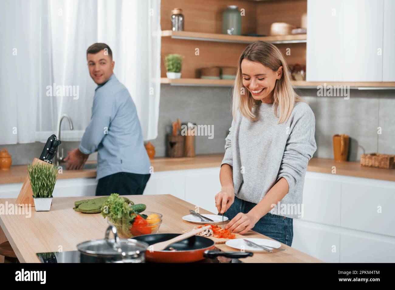 Positive emotions. Couple preparing food at home on the modern kitchen ...
