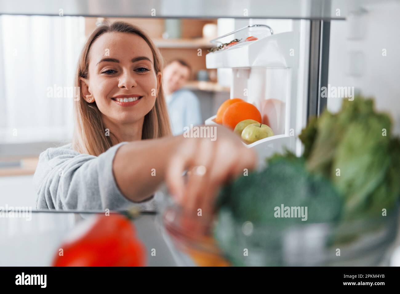 Using vegetables. Couple preparing food at home on the modern kitchen ...