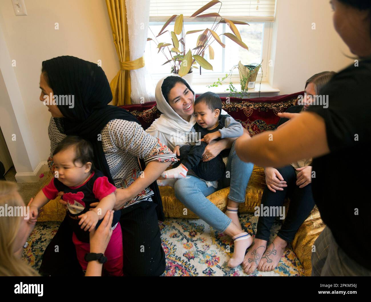 Sima Gul, center, holds her son, Amir Mazlom Yar, as Azizgul Ahmadi, right, reaches for him ...