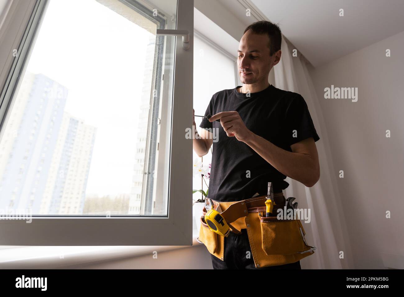 Handyman using a cordless screwdriver to install a window handle ...