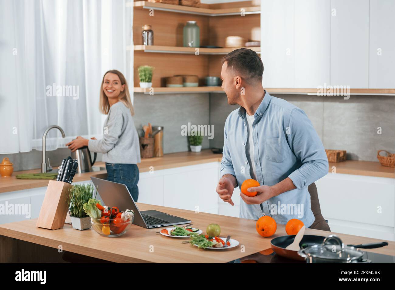 Having weekend together. Couple preparing food at home on the modern ...