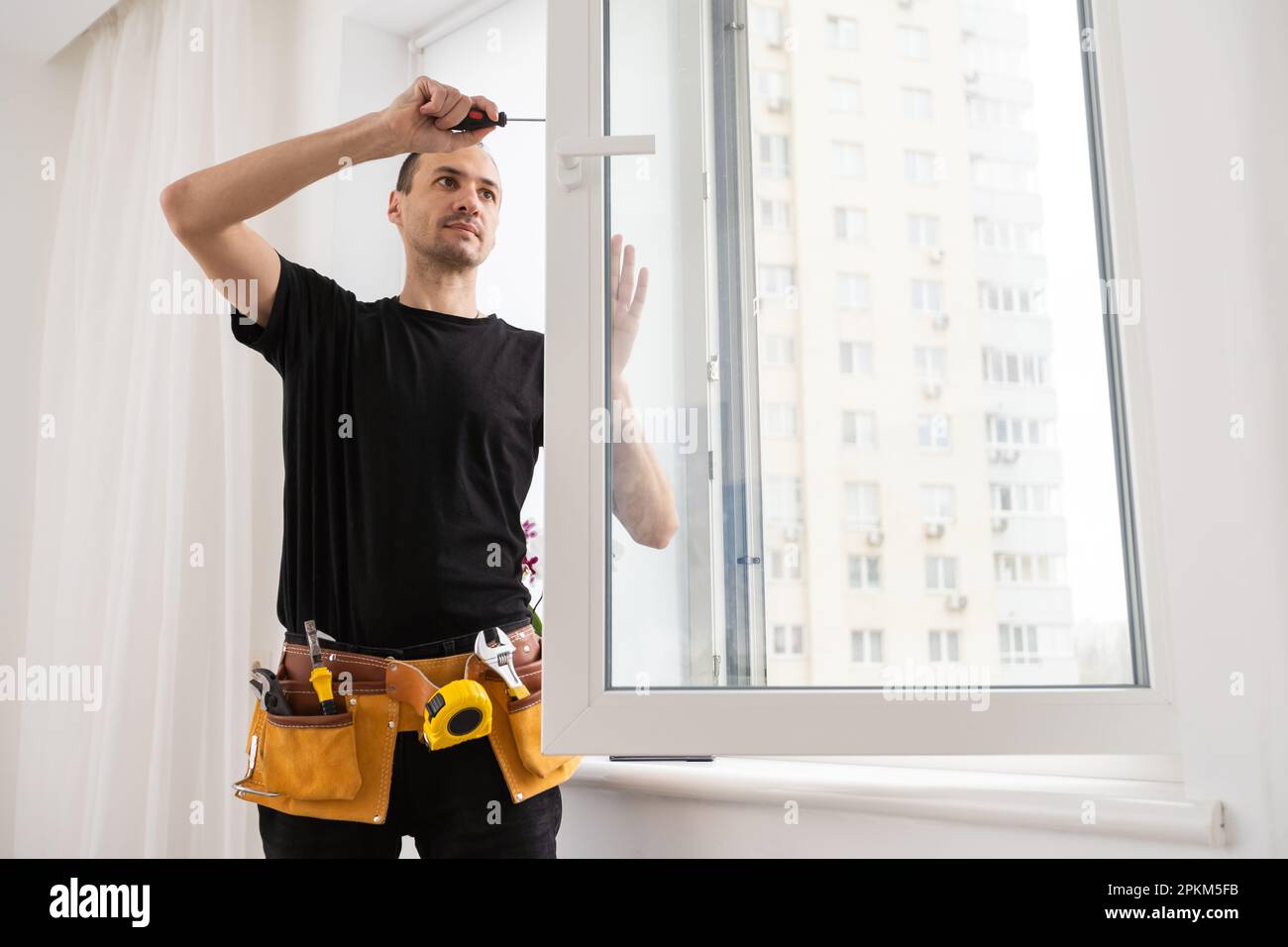 Worker adjusting installed window with screwdriver indoors, closeup ...