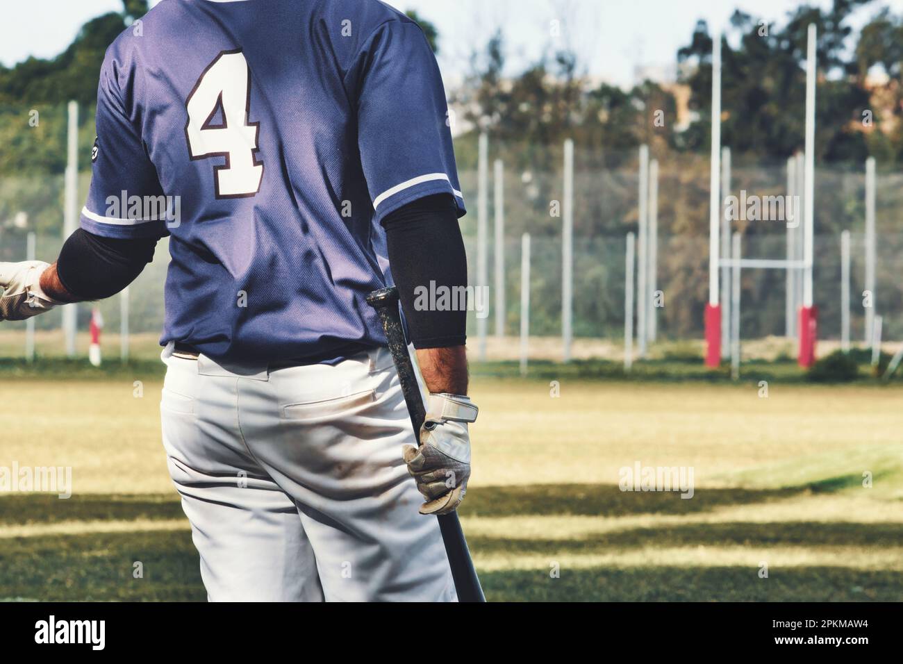 Rear view of a baseball player holding a bat wearing a team uniform on ...