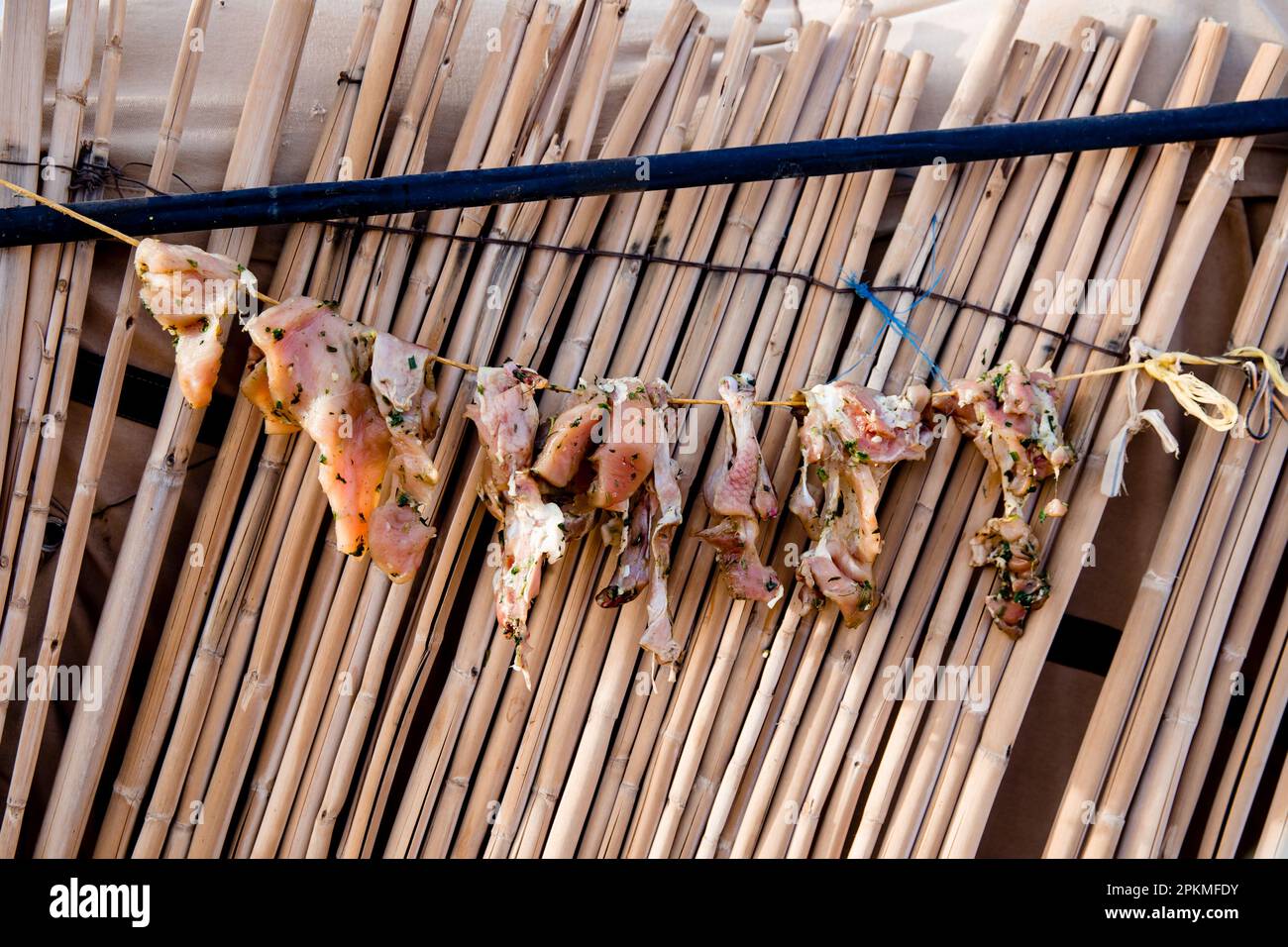 Pieces of chicken hang on a fence to dry in the sun before eating in a ...