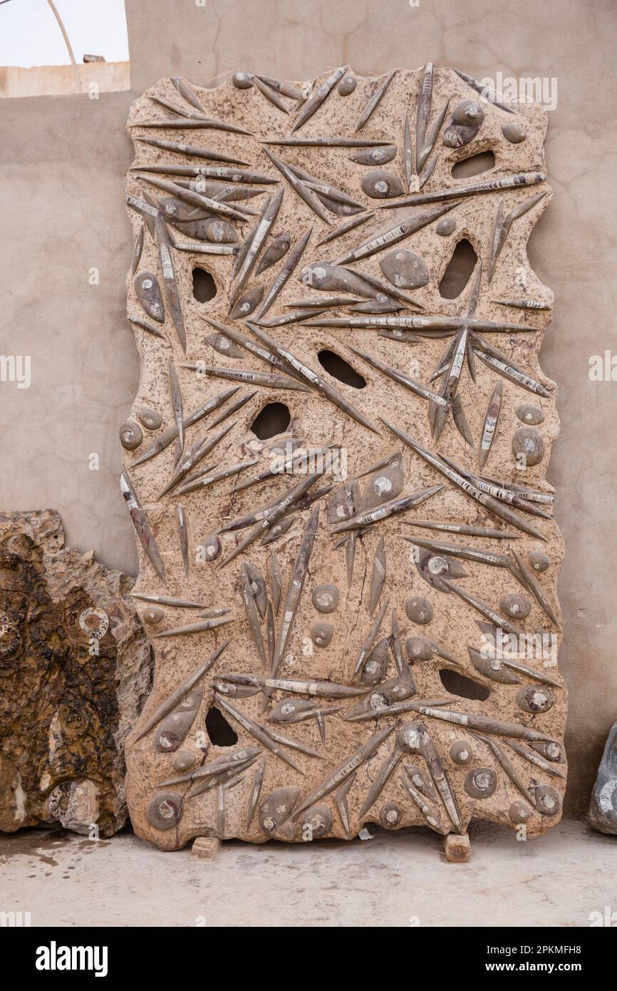 A stone slab sculpture with fossils rests against a wall in Morocco ...