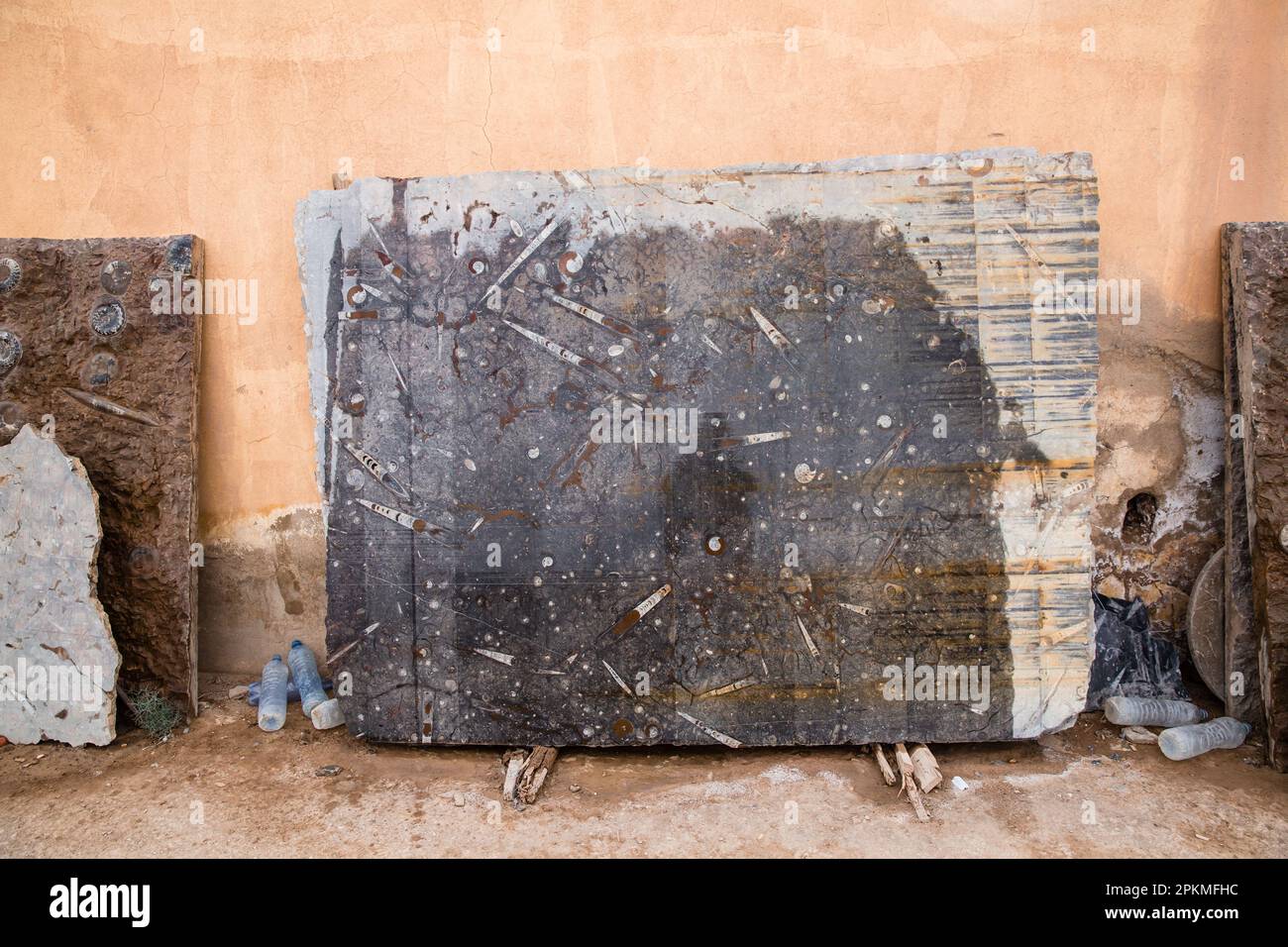 A stone slab filled with fossils rests against a wall in Morocco Stock ...