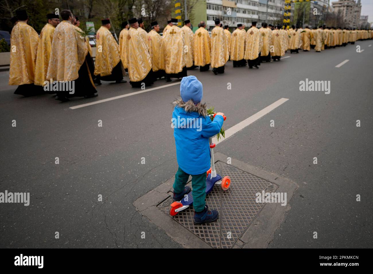 A child stands with his scooter as Romanian Orthodox priests and ...