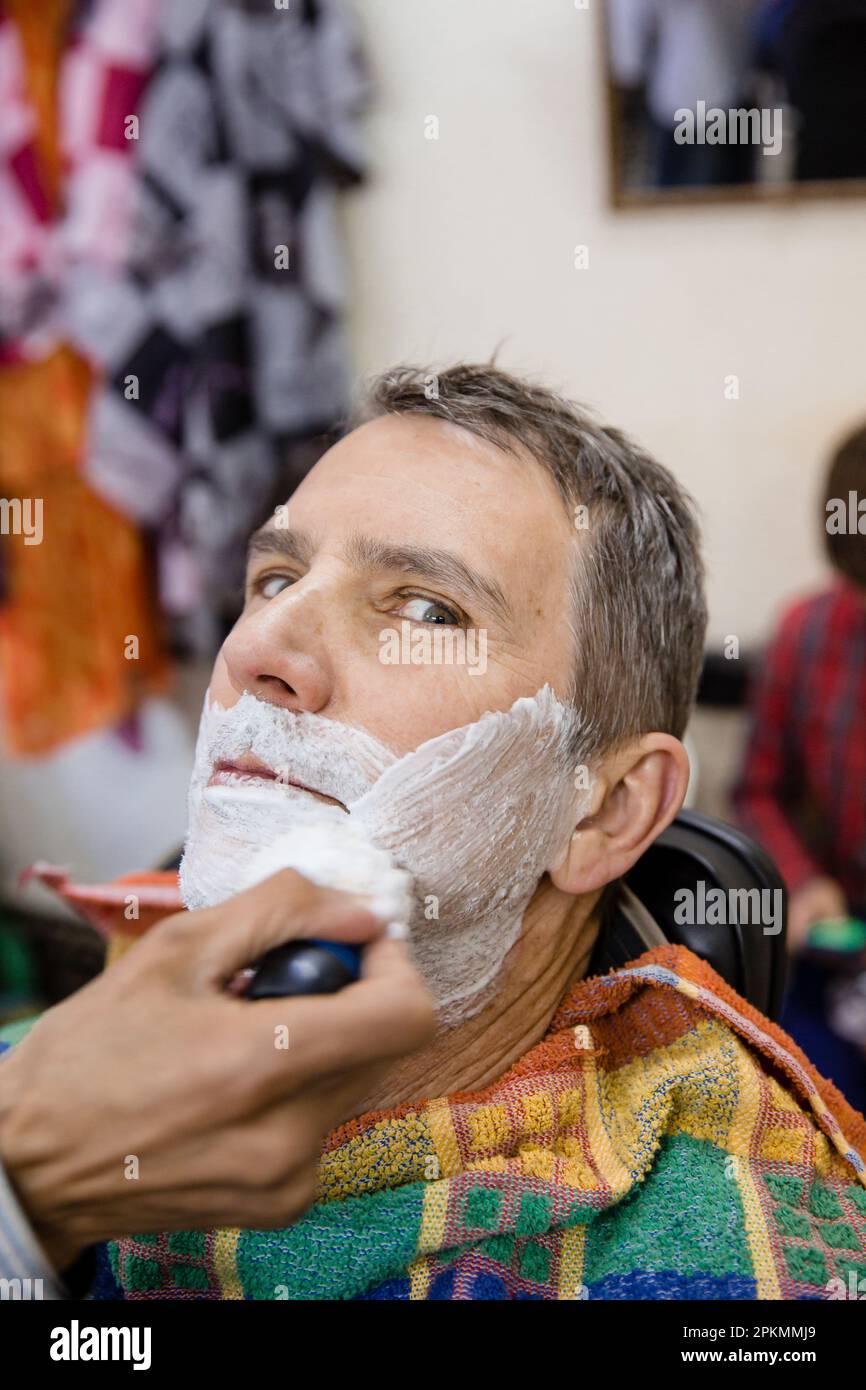 An American tourist getting a straight razor shave at a barbershop in ...