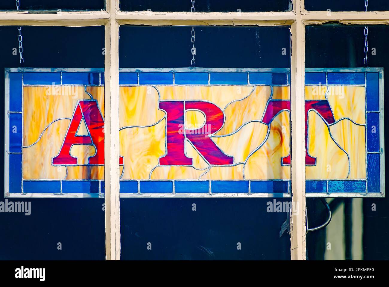 A stained glass sign advertising art hangs in the window of Gulfport ...