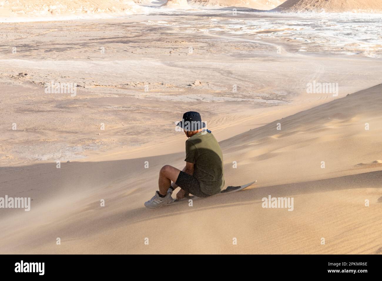 A tourist sandboarding down a slope in a desert near Bahariya in Egypt ...