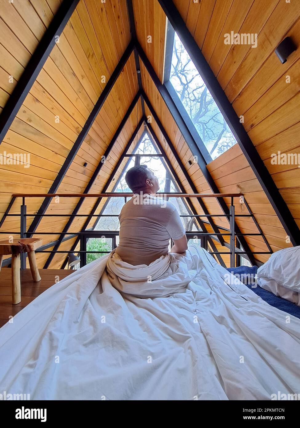 Dark-haired Latino adult man wakes up in the morning on a bed stretches ...
