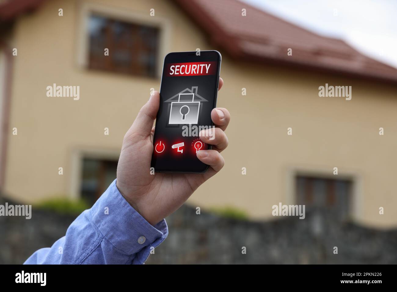 Man using home security application on smartphone in front of house ...