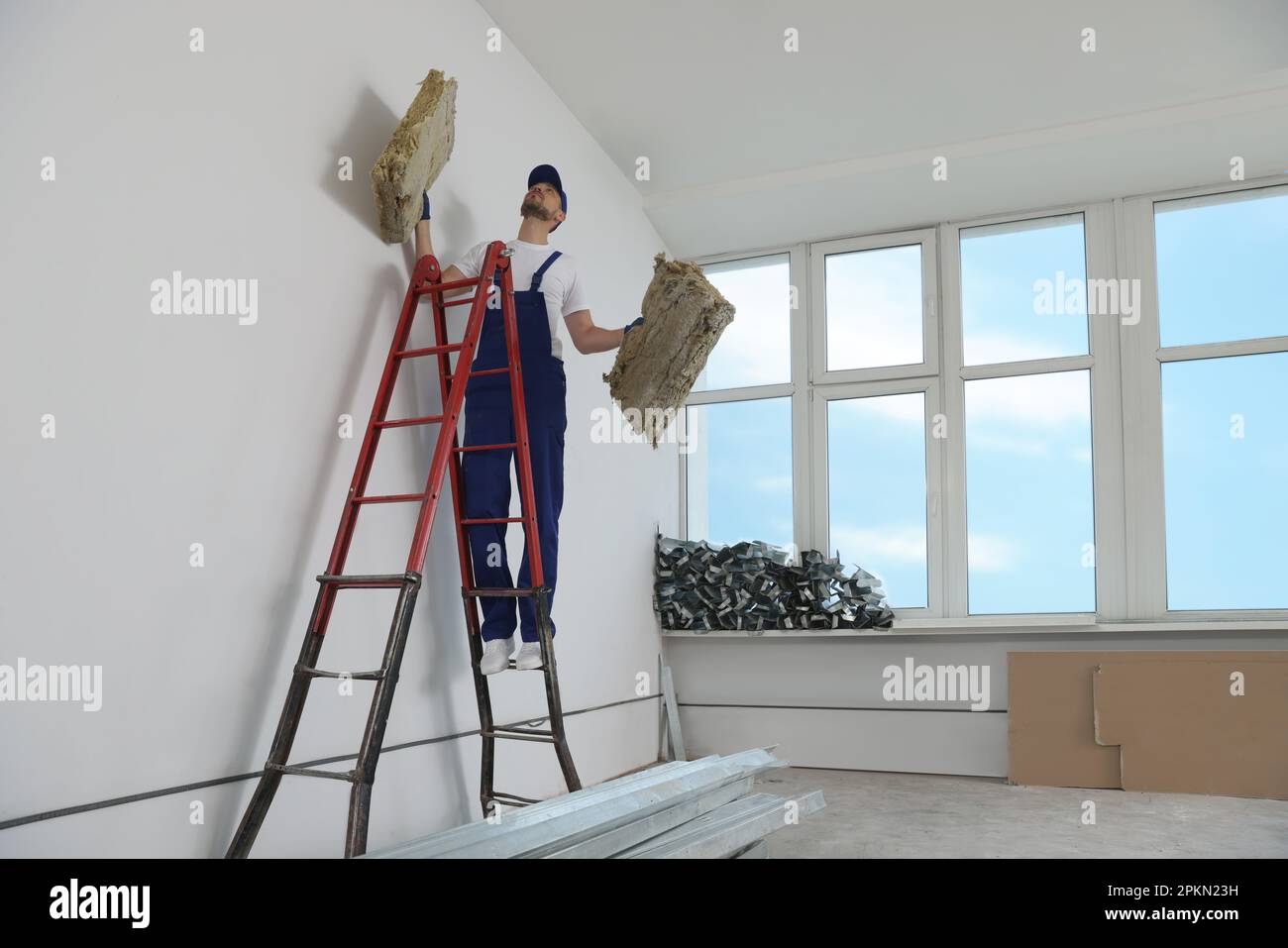 Construction worker with used glass wool on stepladder in room prepared ...