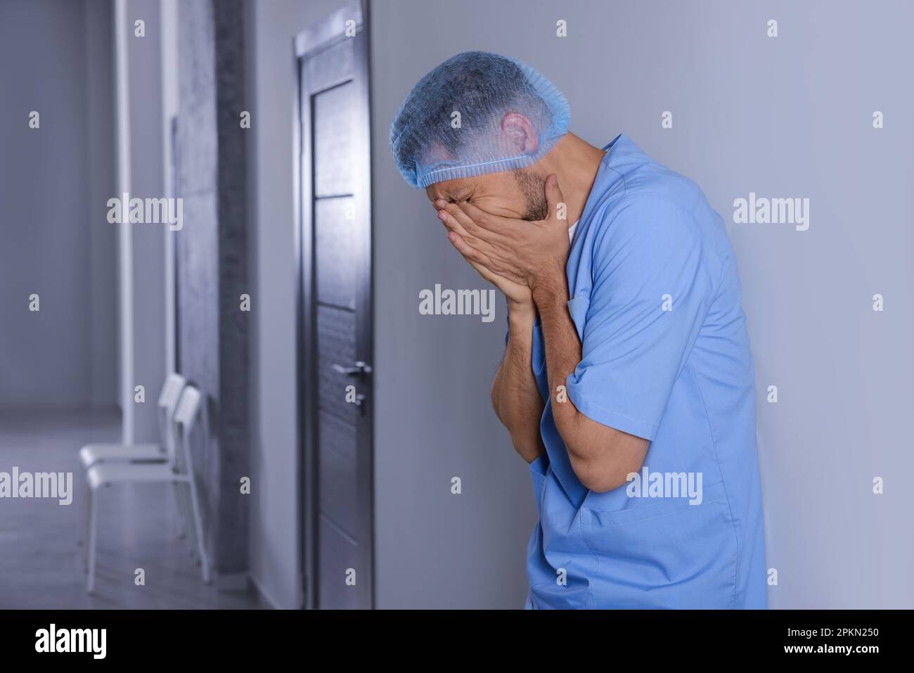 Crying doctor near grey wall in hospital, space for text Stock Photo ...