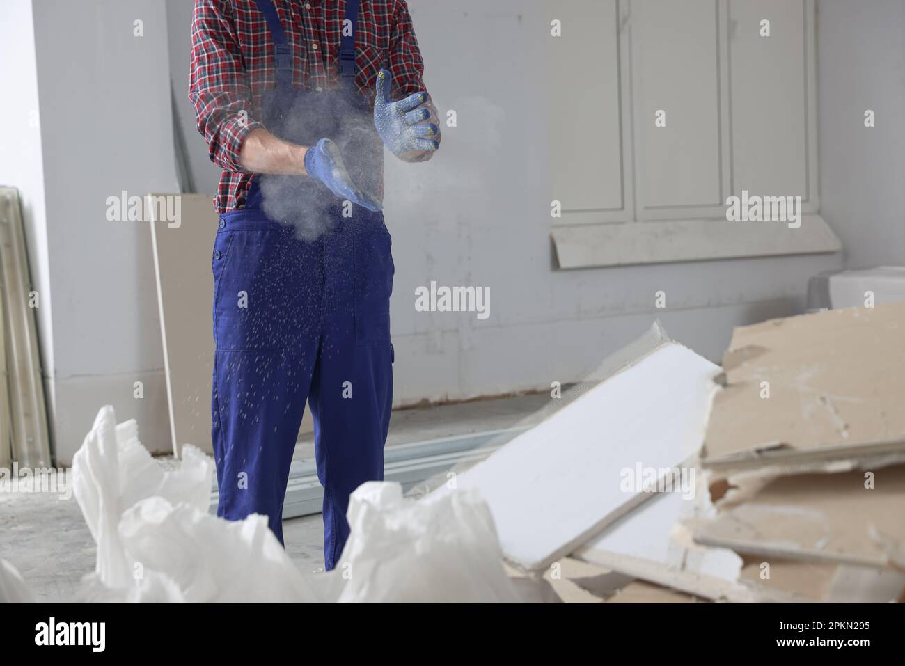Construction worker shaking off dust from hands in room prepared for ...