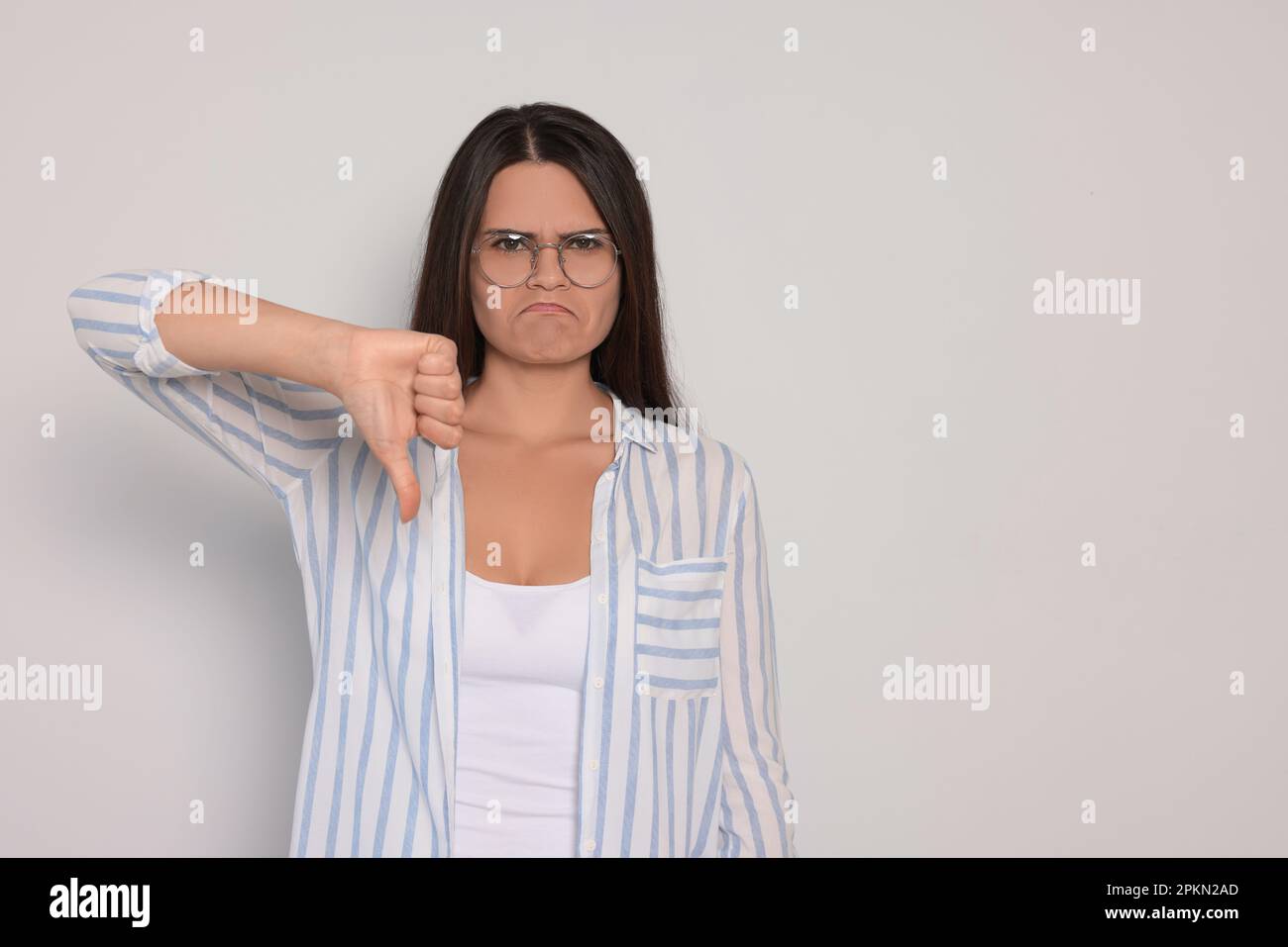 Young woman showing thumb down on white background, space for text ...