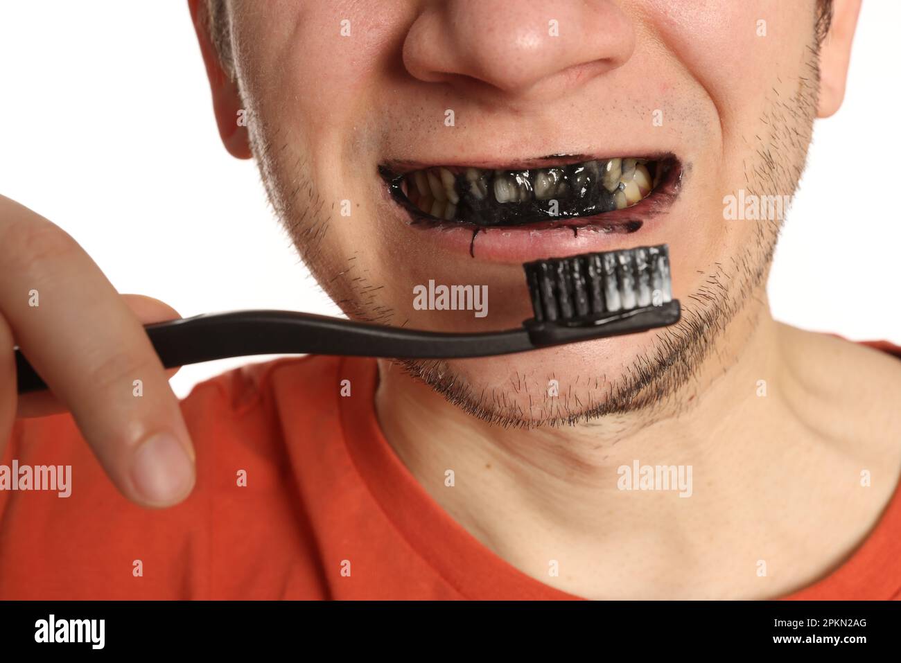 Man Brushing Teeth With Charcoal Toothpaste On White Background