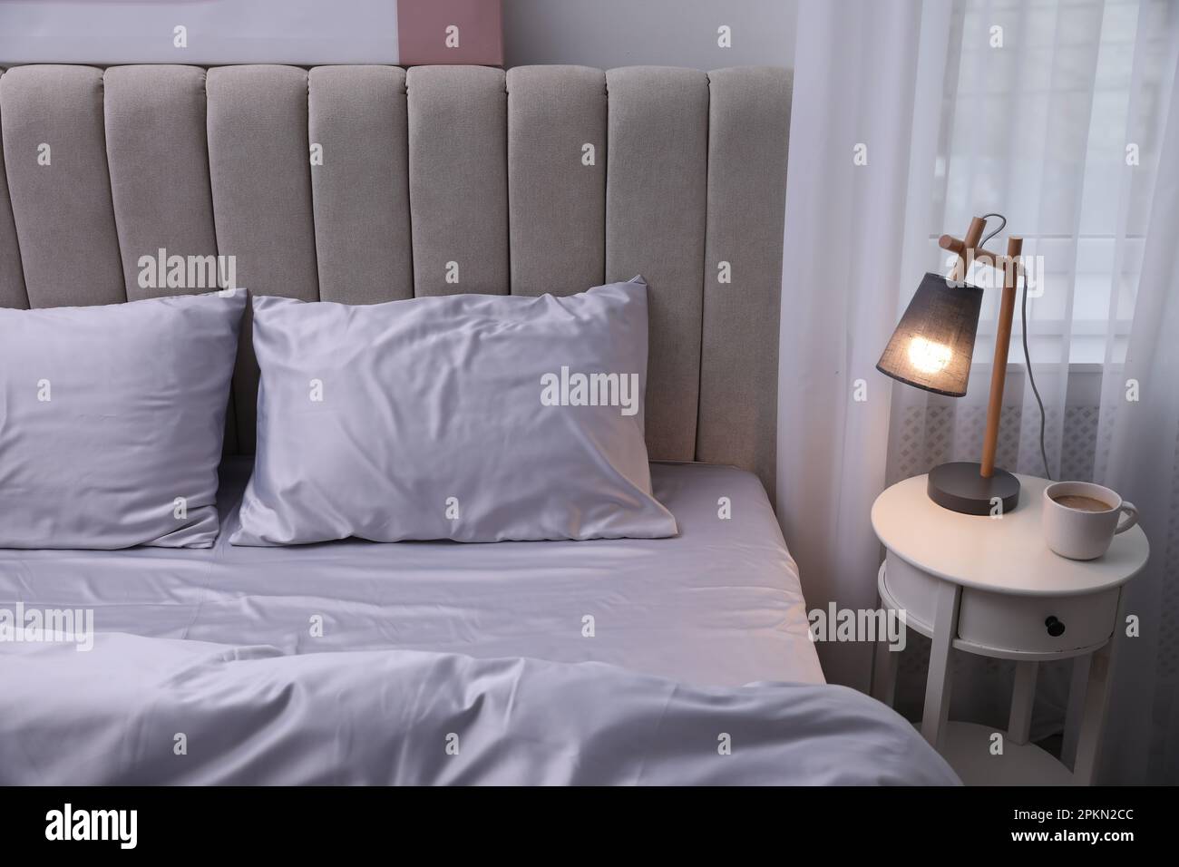 Cozy bed with soft silky bedclothes in light room Stock Photo - Alamy