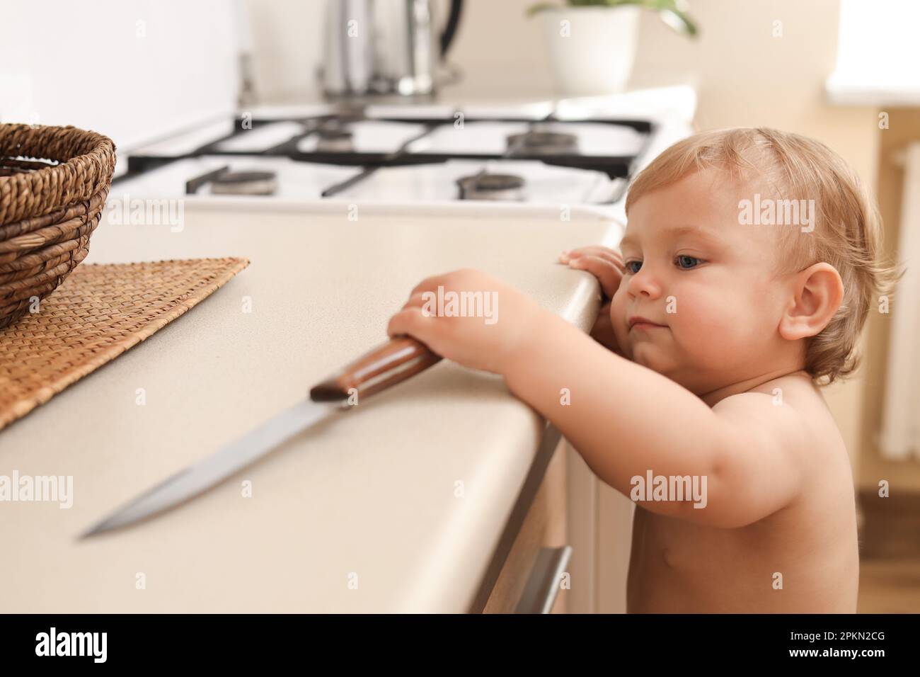 Little child holding sharp knife in kitchen. Dangerous situation Stock ...