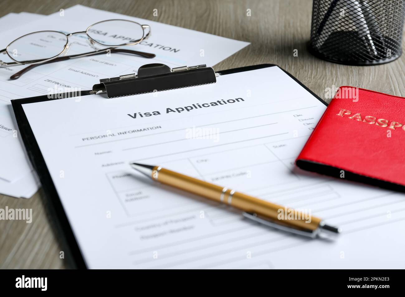 Visa application form for immigration, passport and pen on table ...