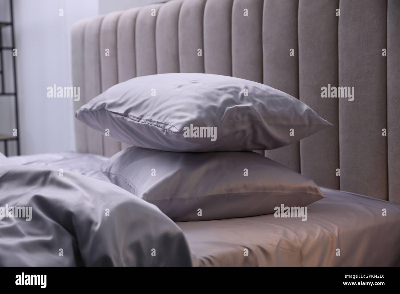 Cozy bed with soft silky bedclothes in light room Stock Photo - Alamy