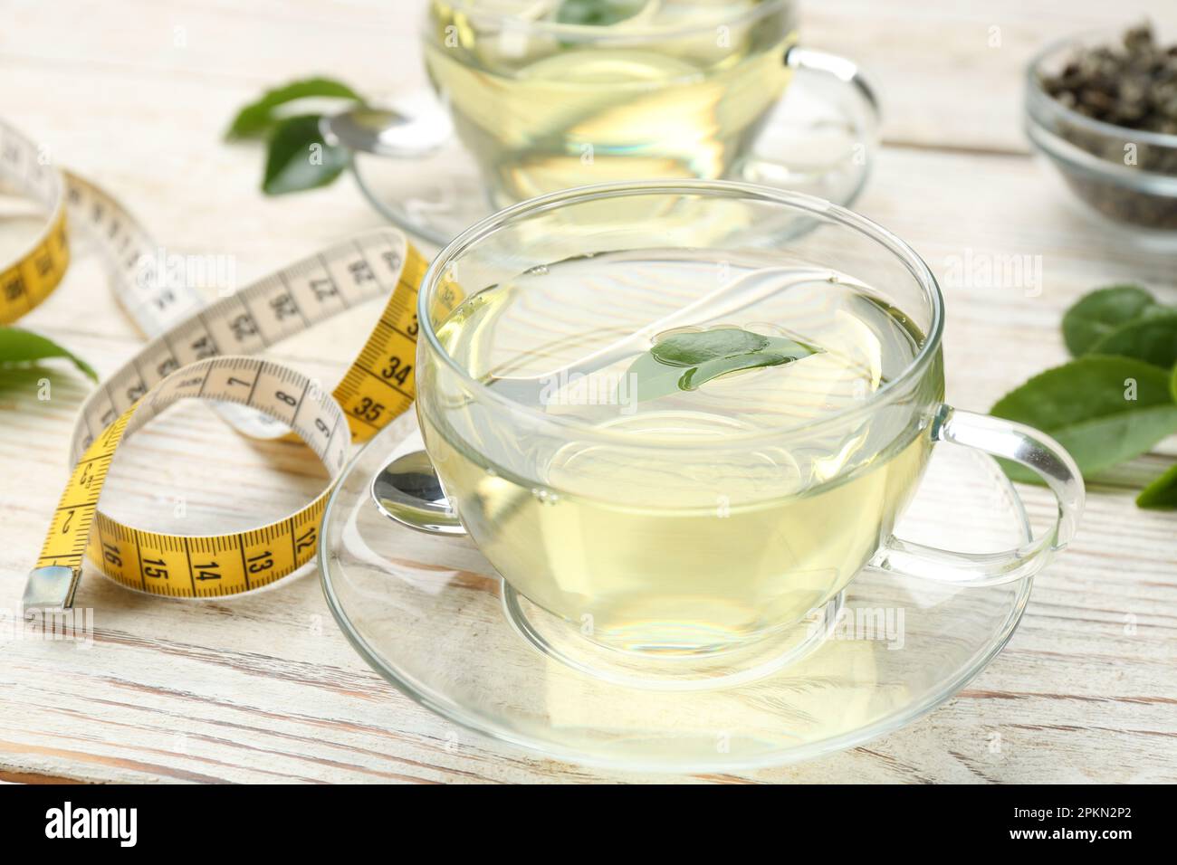 Diet herbal tea with green leaf and measuring tape on white wooden ...