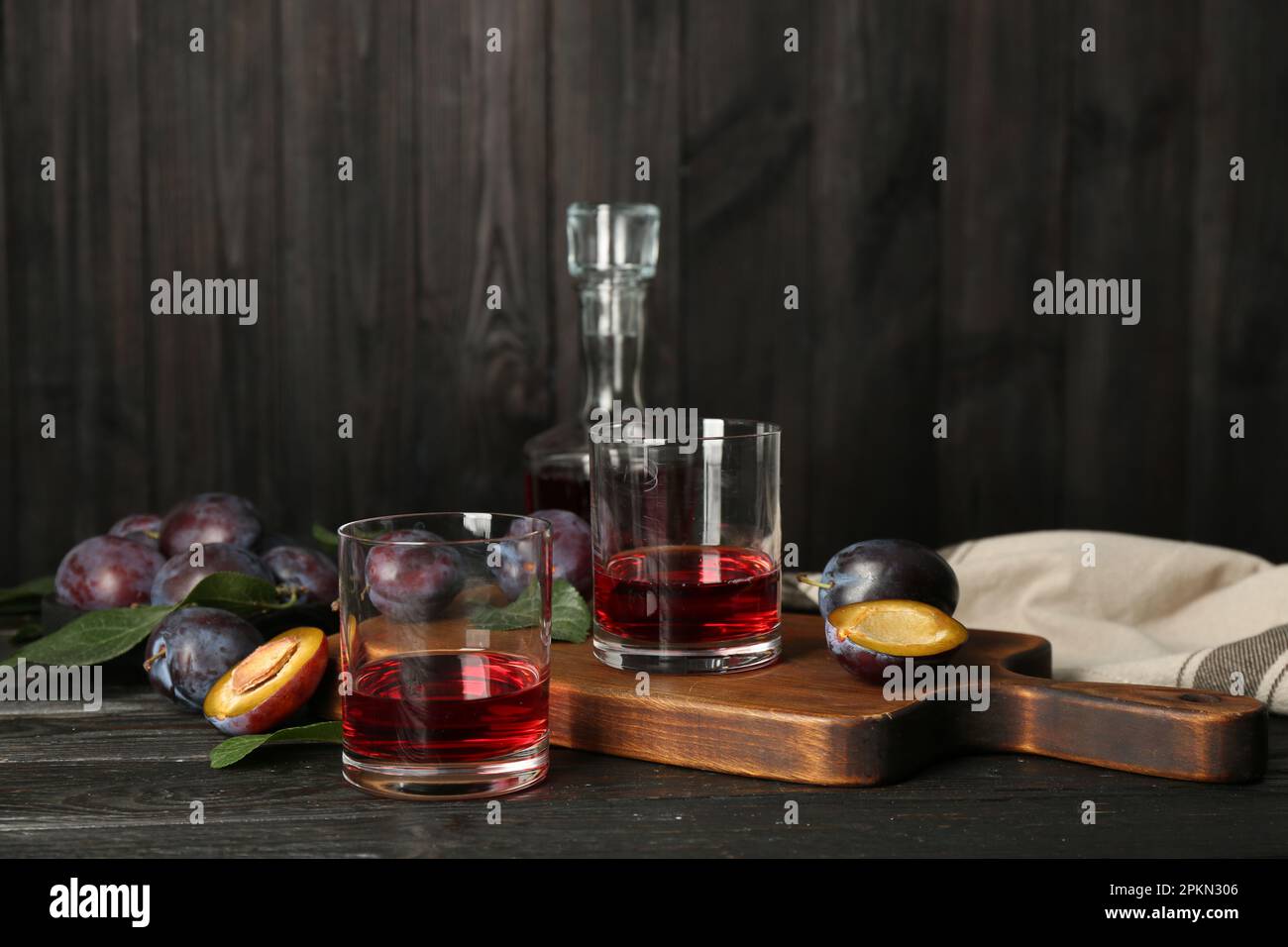 Delicious plum liquor and ripe fruits on black wooden table. Homemade ...
