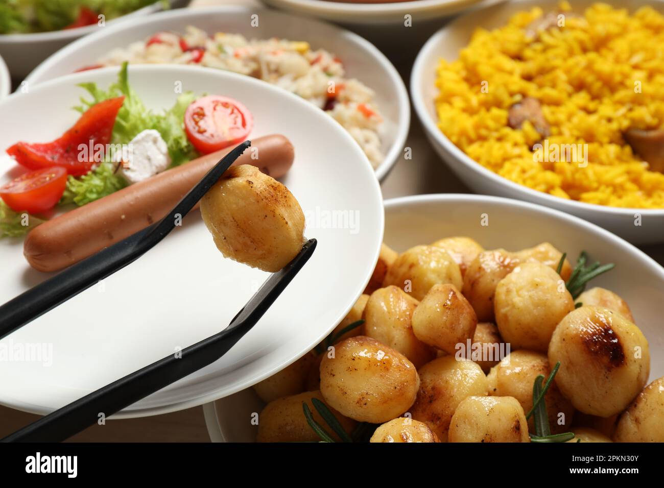 Taking roasted potato from buffet table, closeup Stock Photo - Alamy