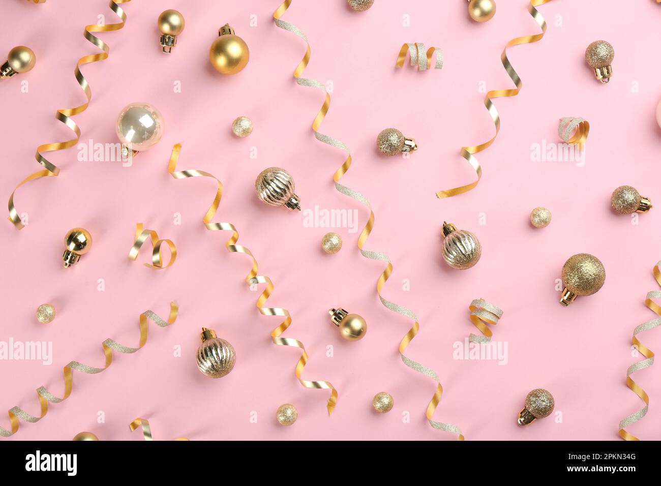 Shiny serpentine streamers and Christmas balls on pink background, flat ...