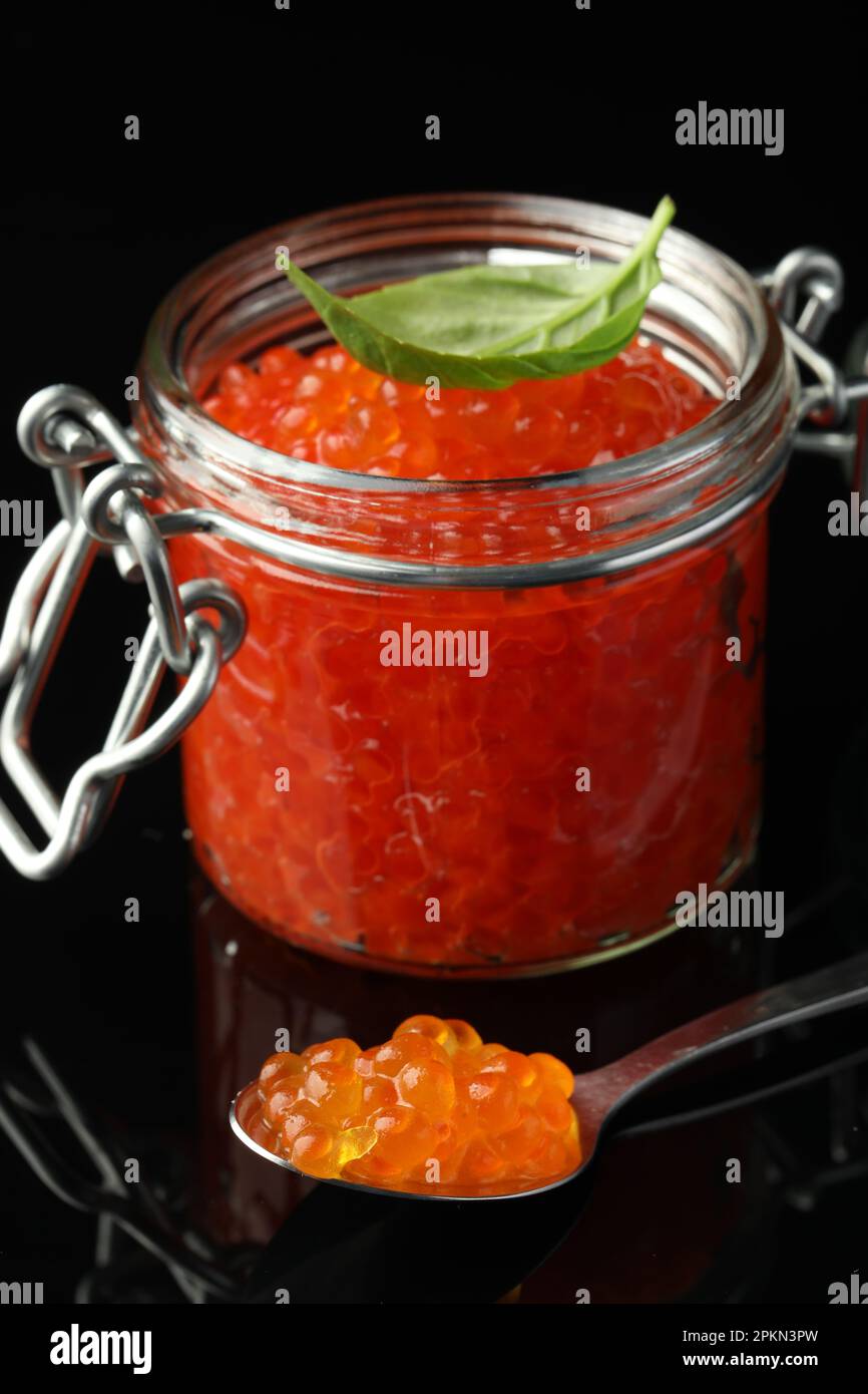 Delicious red caviar and basil leaf on black background Stock Photo - Alamy