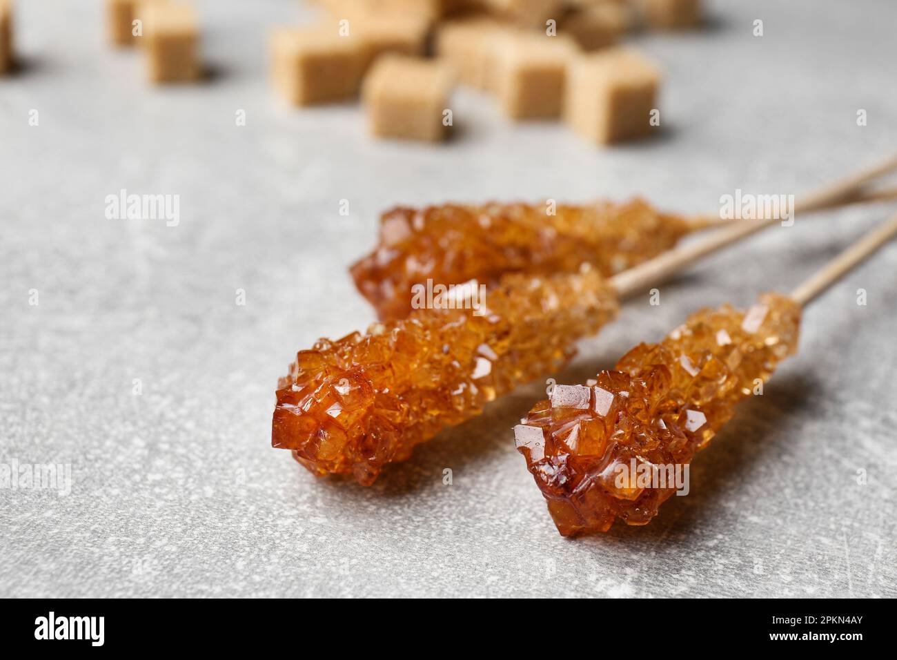 Sticks with sugar crystals on light grey table, closeup. Tasty rock ...